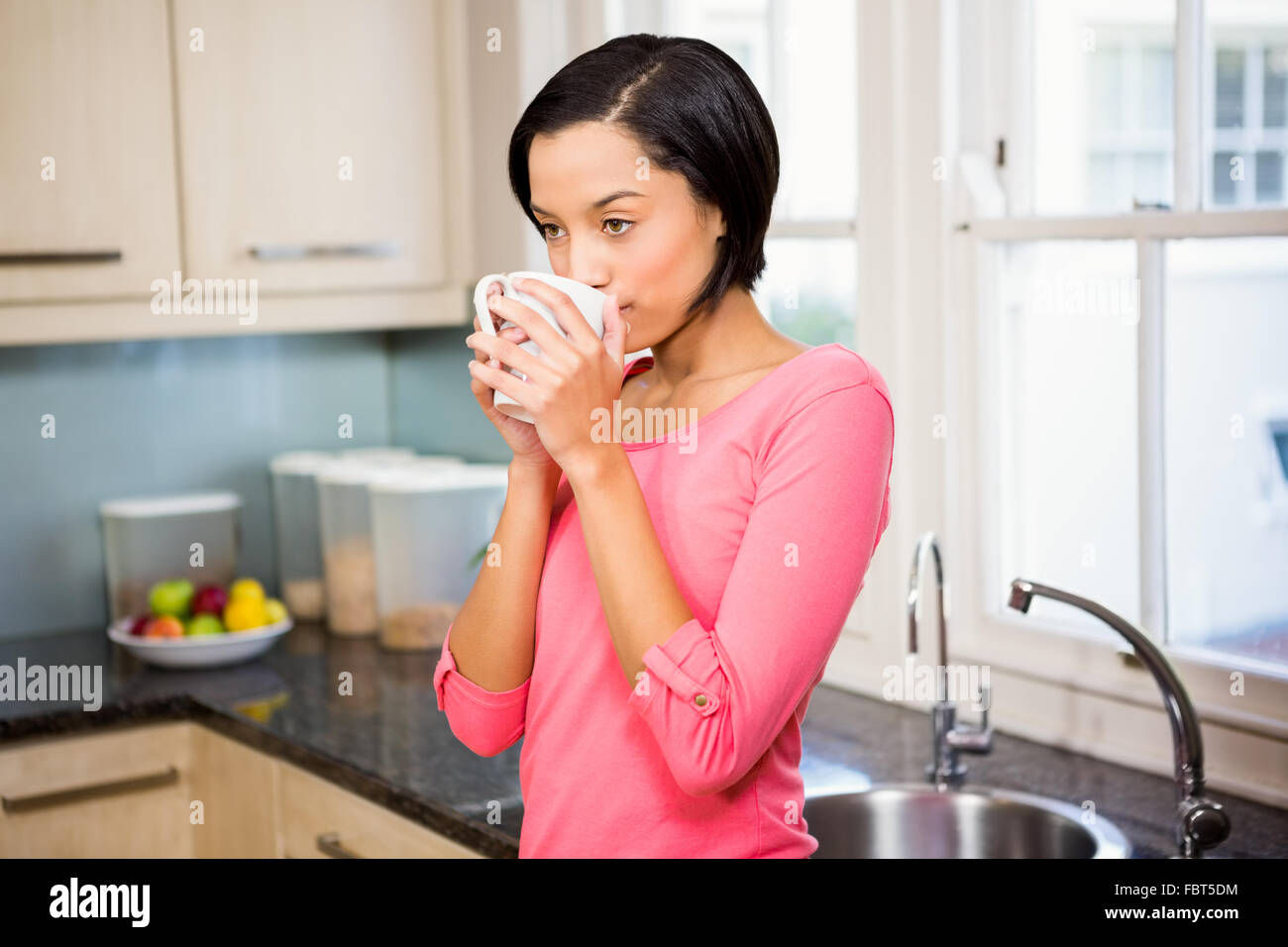 Standing brunette drinking by cup Stock Photo - Alamy