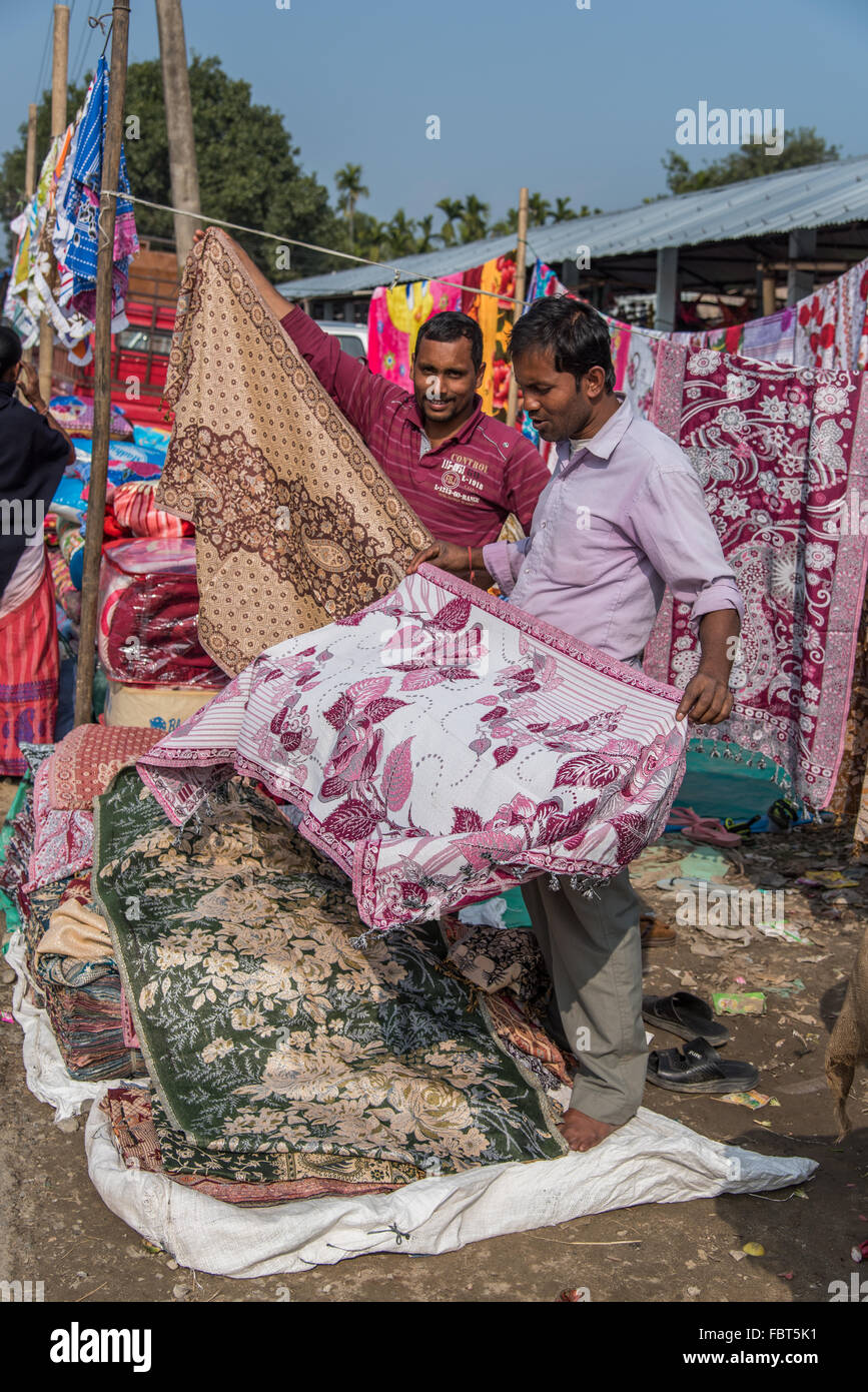 Indian market. 2 male market traders hold up fabric for sale at the ...