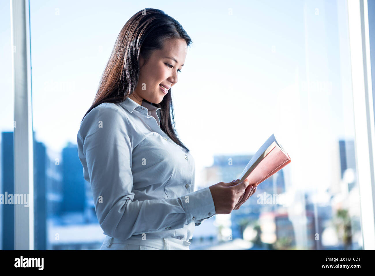 Smiling businesswoman reading book Stock Photo - Alamy