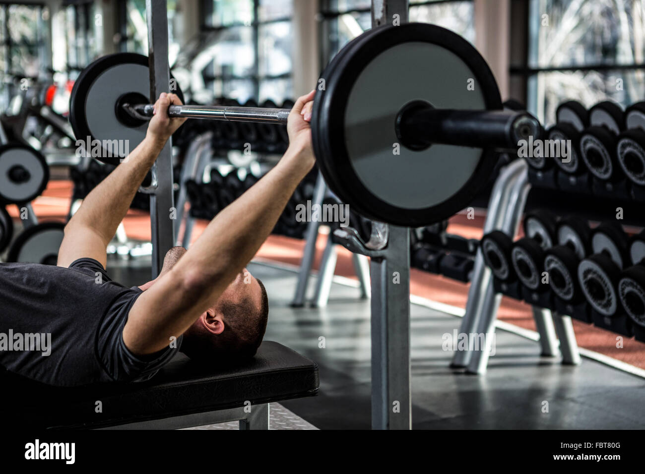 Muscular man lifting barebell while lying on bench Stock Photo - Alamy