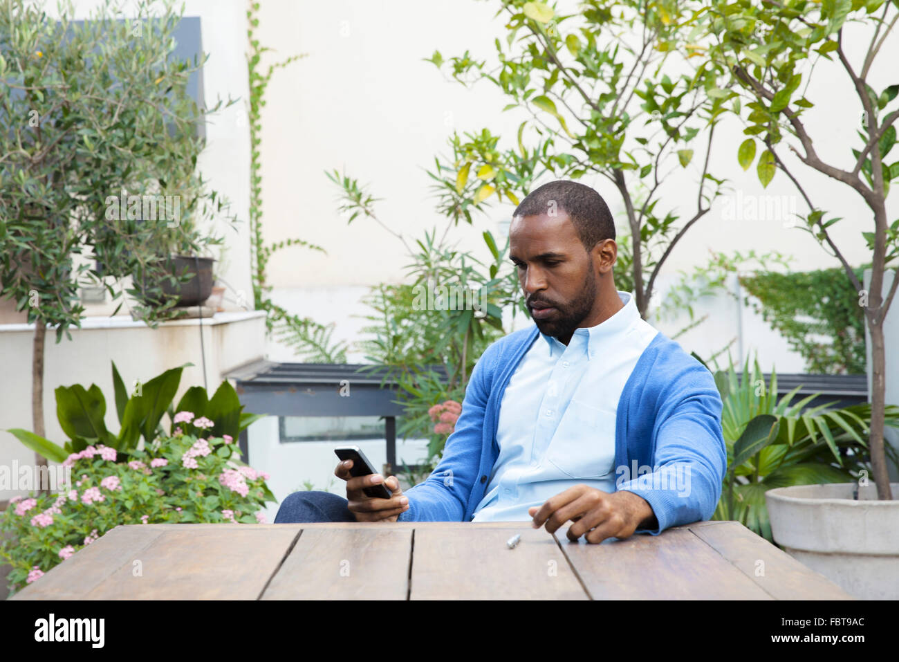 Man seated at table in courtyard making phone call Stock Photo - Alamy