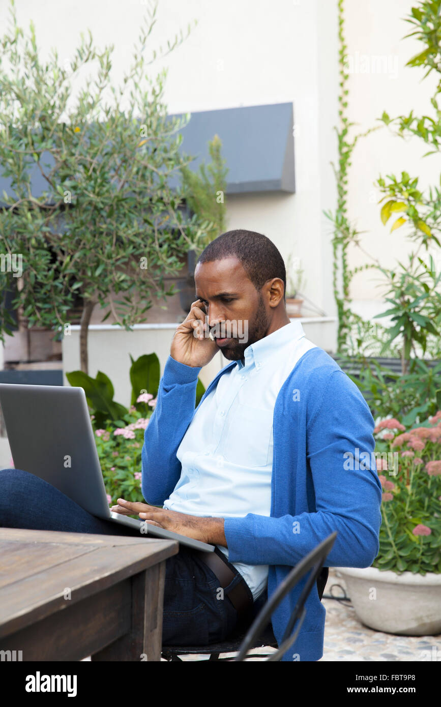 Man making phone call while using laptop computer outdoors Stock Photo ...