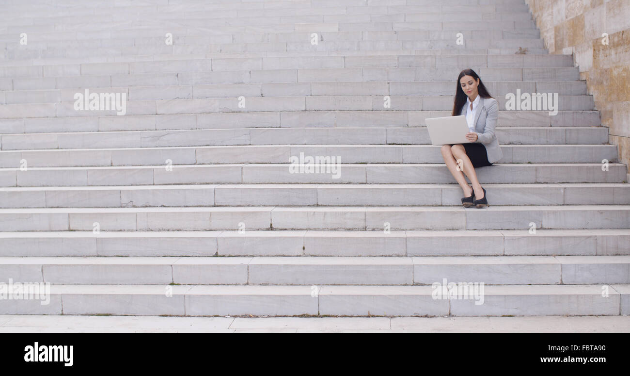 Cute young business woman in high heels sitting outdoors on staircase ...