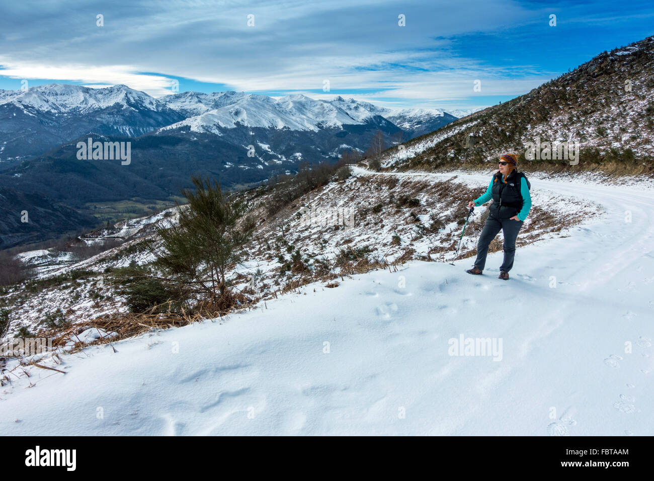 Female in black on snow and ice covered road with distant snowy ...