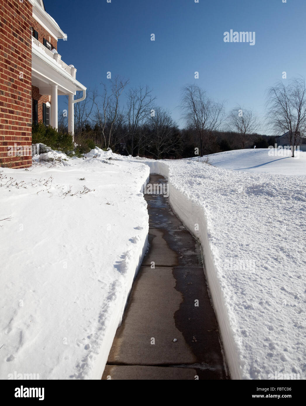 Pathway cut through deep snow towards the door of a modern single ...