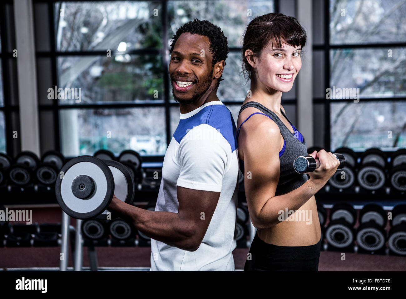 Fit couple lifting dumbbells back to back Stock Photo - Alamy