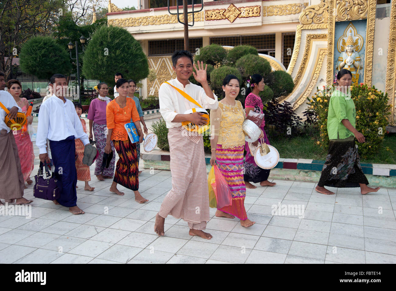 Father waves in a procession of Burmese children dressed in traditional ...