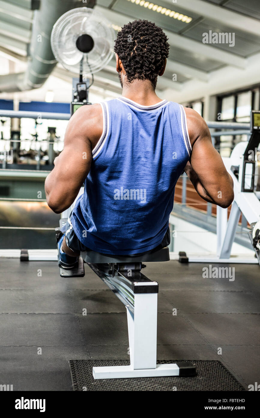 Muscular man using rowing machine Stock Photo - Alamy