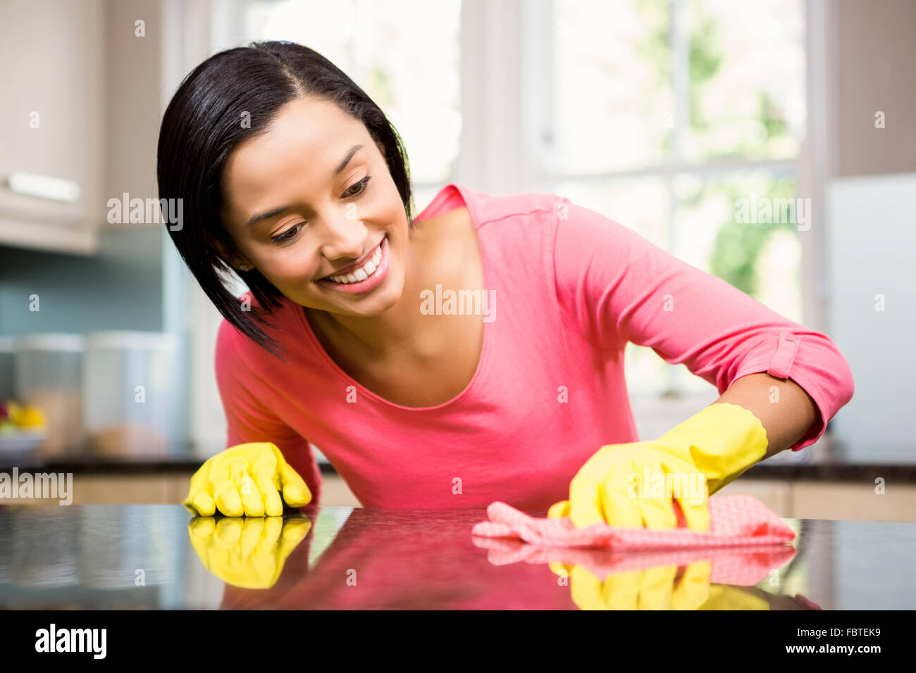 Smiling brunette cleaning kitchen counter Stock Photo - Alamy