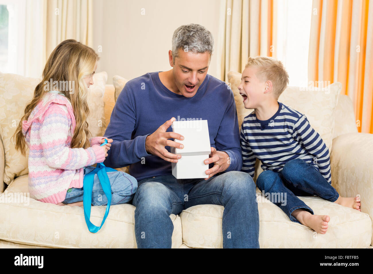 Father opening gift given by children on sofa Stock Photo - Alamy