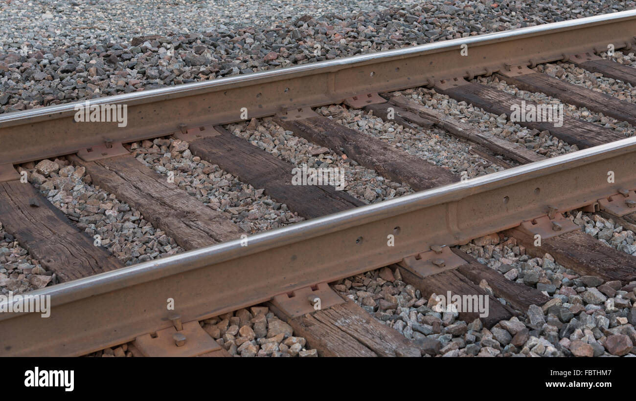 Steel railroad tracks, ties and spikes sitting on a gravel bed ready ...