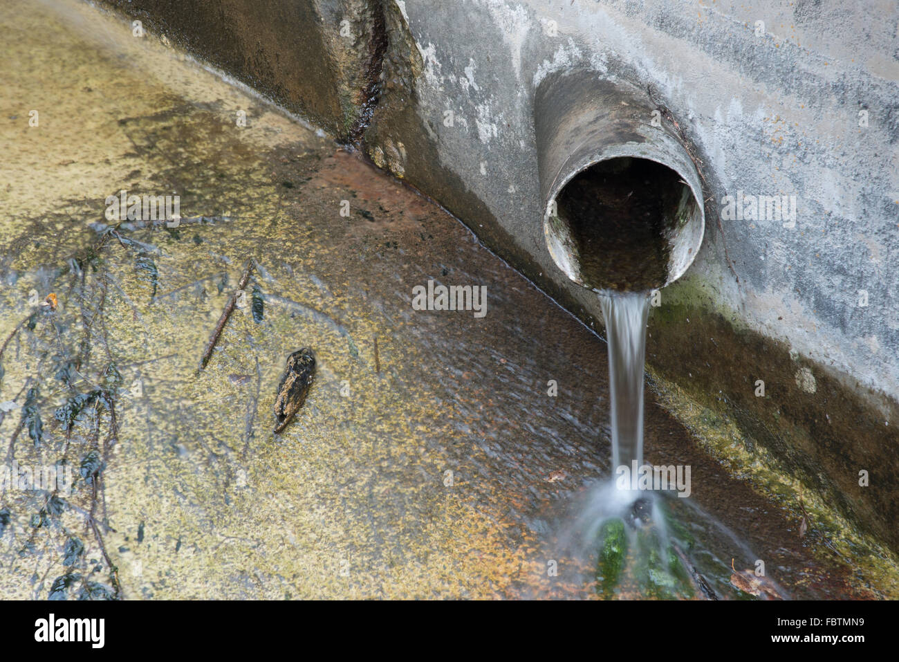 Drainage pipe protruding from a concrete wall into a stream Stock Photo ...