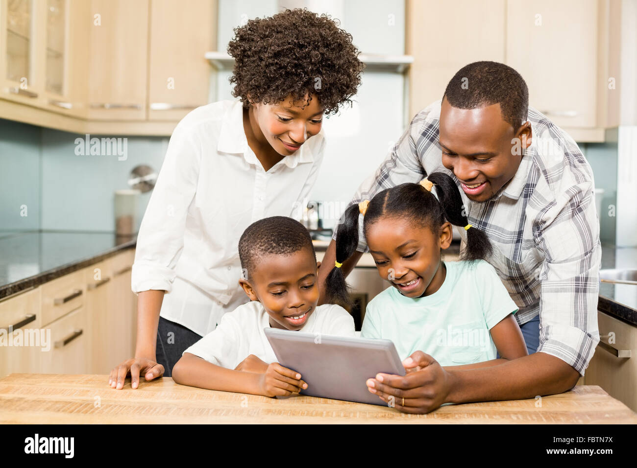 Happy family using tablet in kitchen Stock Photo - Alamy