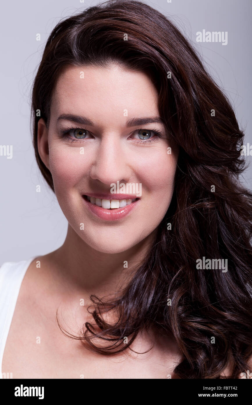 Smiling attractive woman with a lovely warm friendly smile and shoulder ...