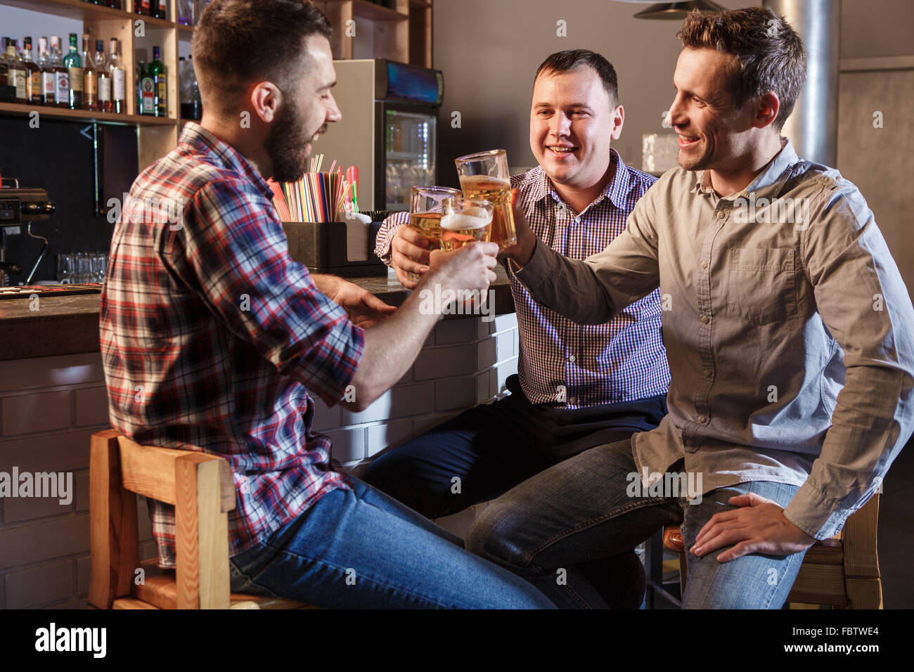 Happy friends drinking beer at counter in pub Stock Photo - Alamy