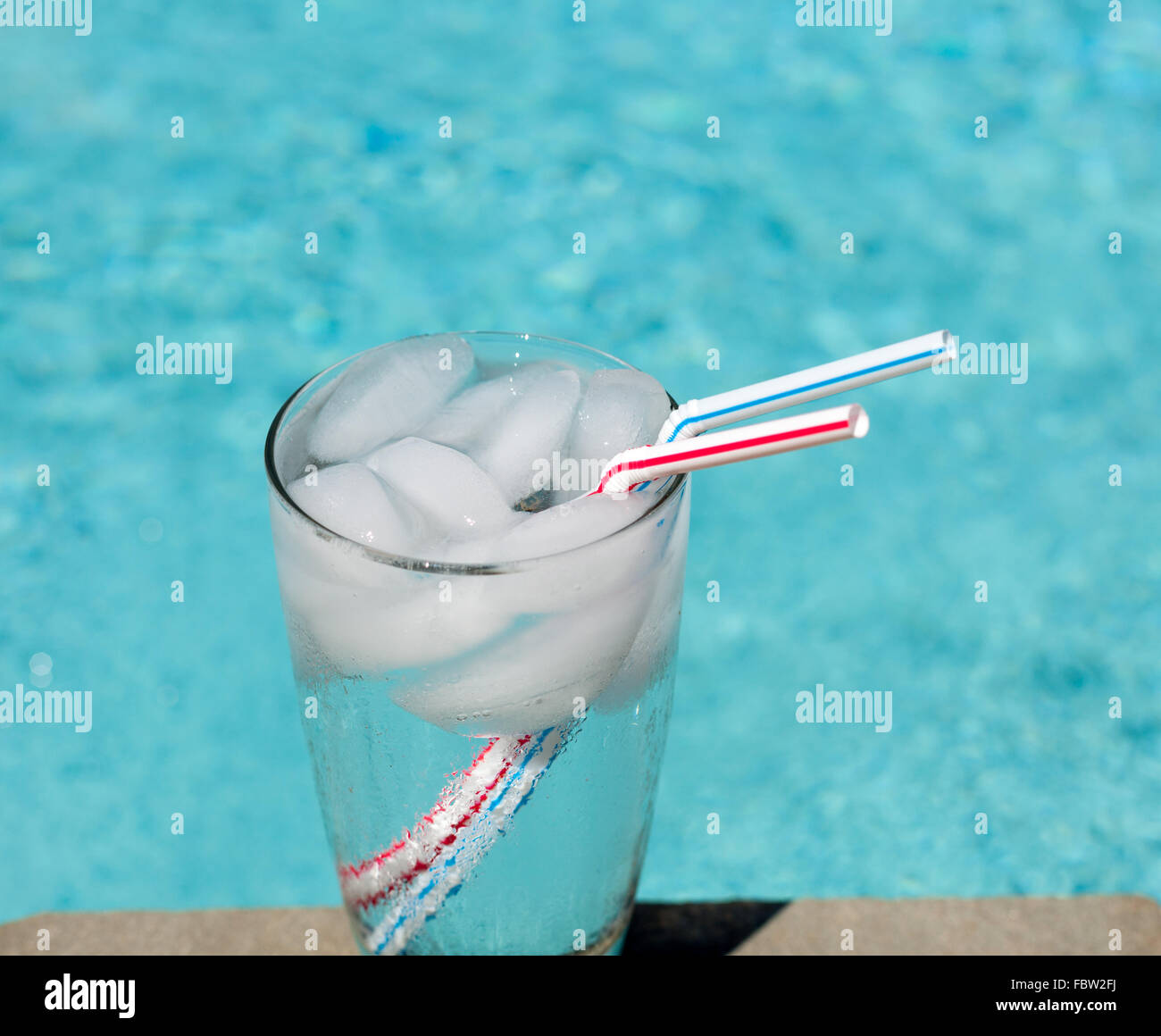 Glass of water with ice cubes on side of pool Stock Photo - Alamy