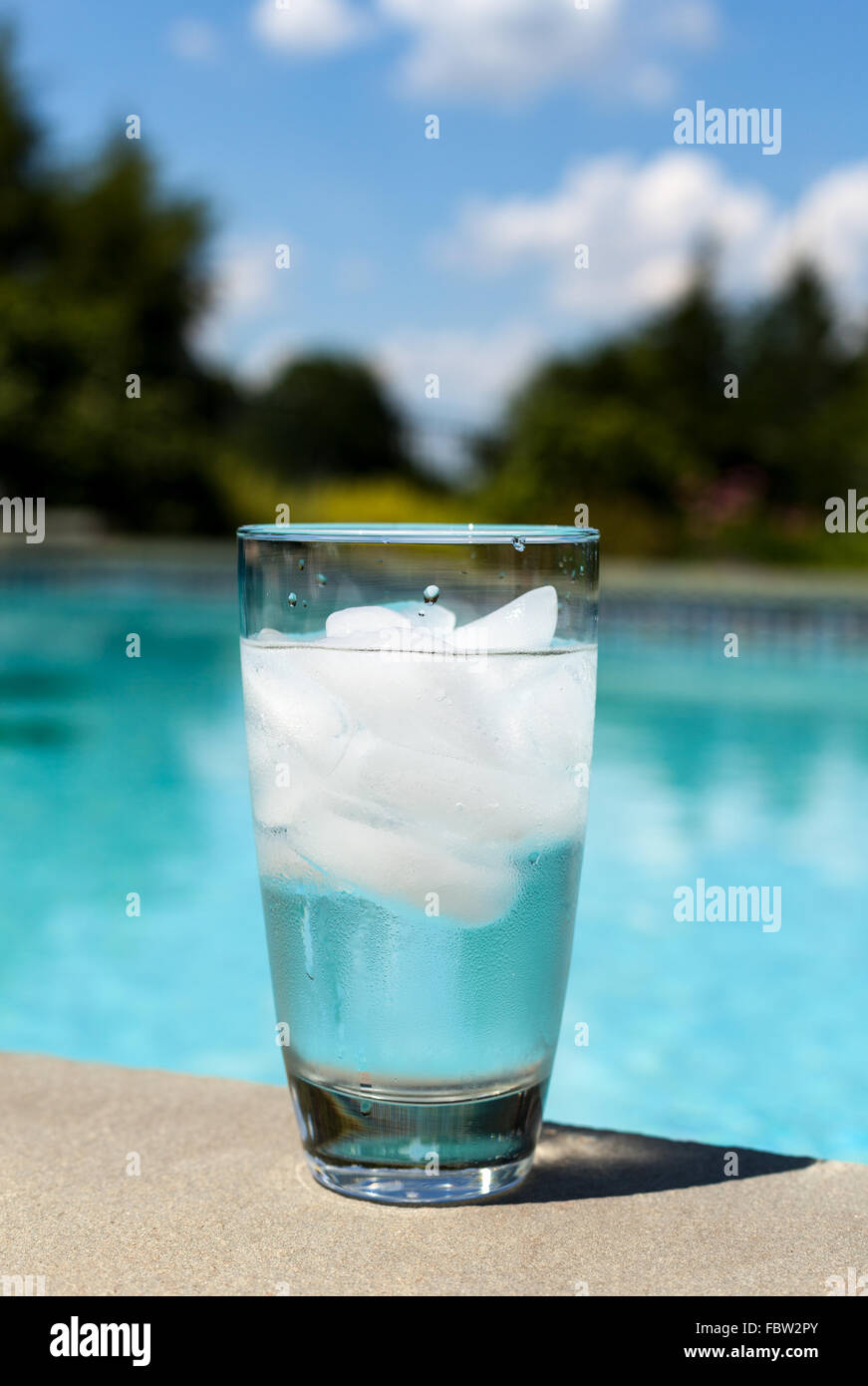 Glass of water with ice cubes on side of pool Stock Photo - Alamy