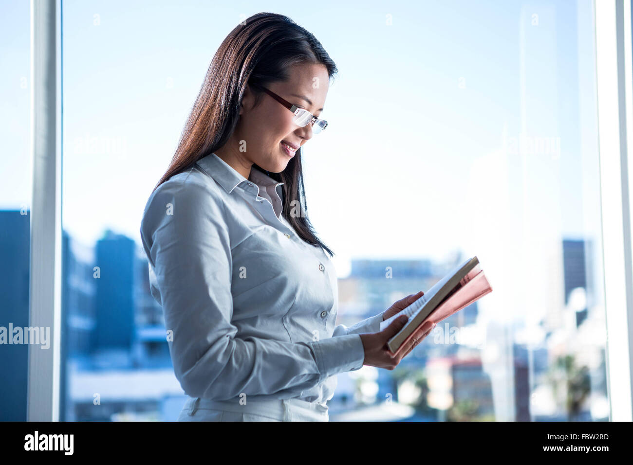 Smiling businesswoman reading book Stock Photo - Alamy