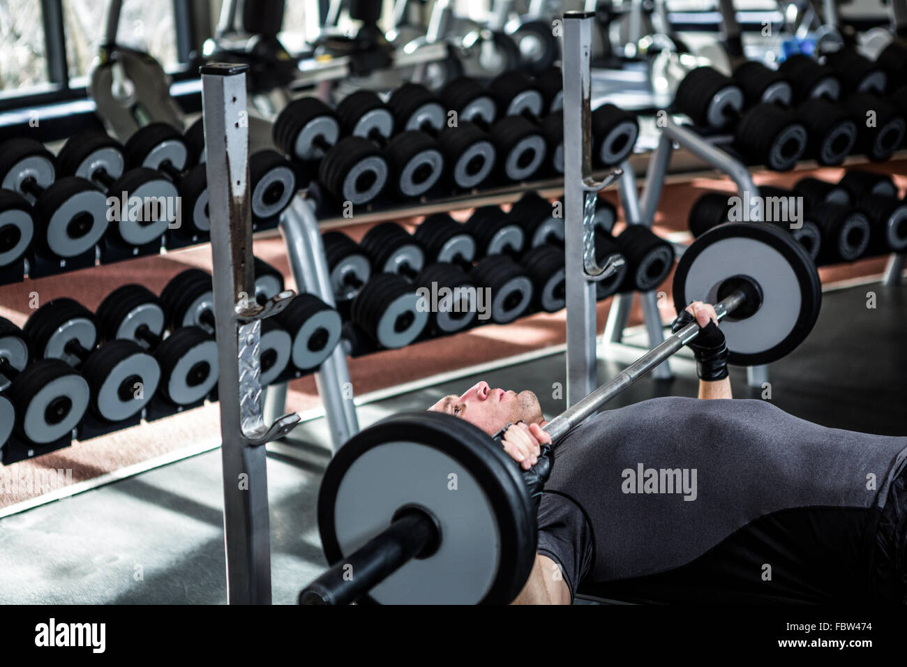 Muscular man lifting barebell while lying on bench Stock Photo - Alamy