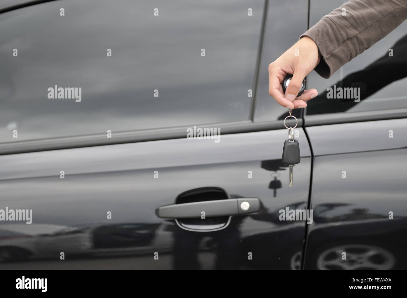 male hand holding car key with new black car in background Stock Photo ...