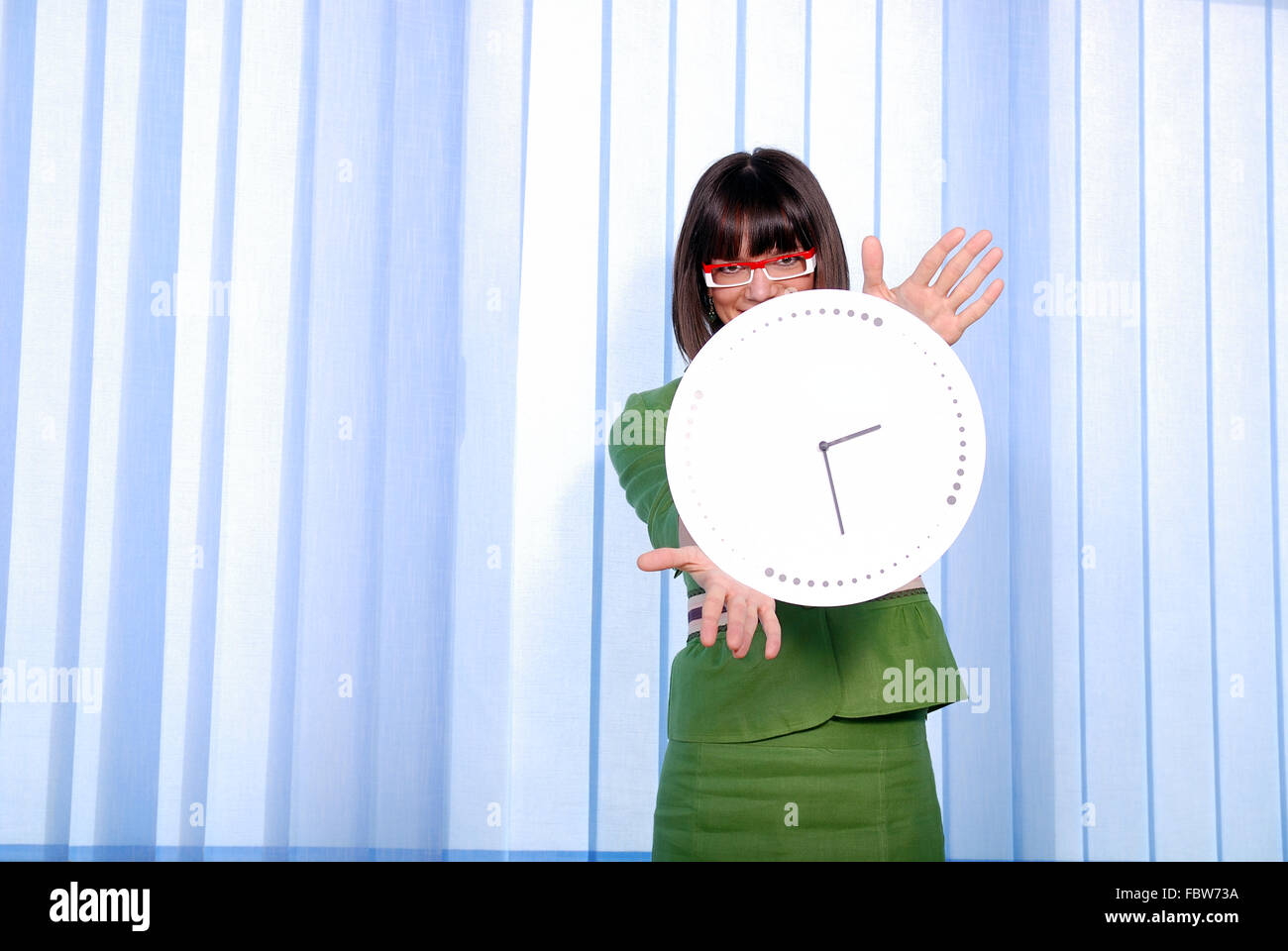 .a pretty business woman hiding behind a clock Stock Photo - Alamy