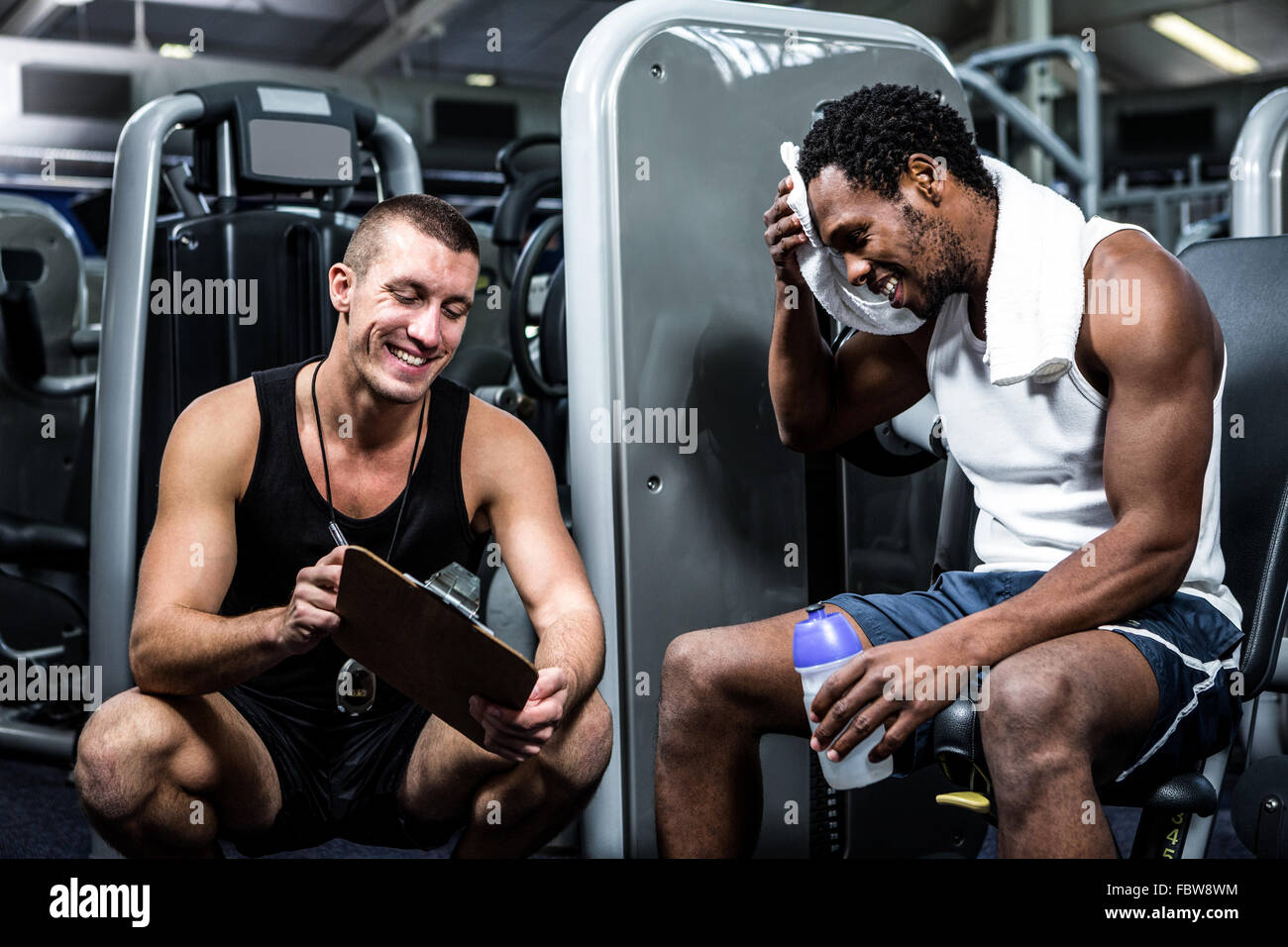 Muscular man discussing performance with trainer Stock Photo - Alamy