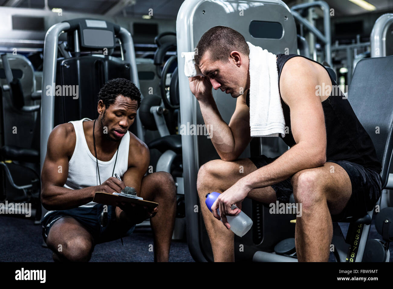 Muscular man discussing performance with trainer Stock Photo - Alamy