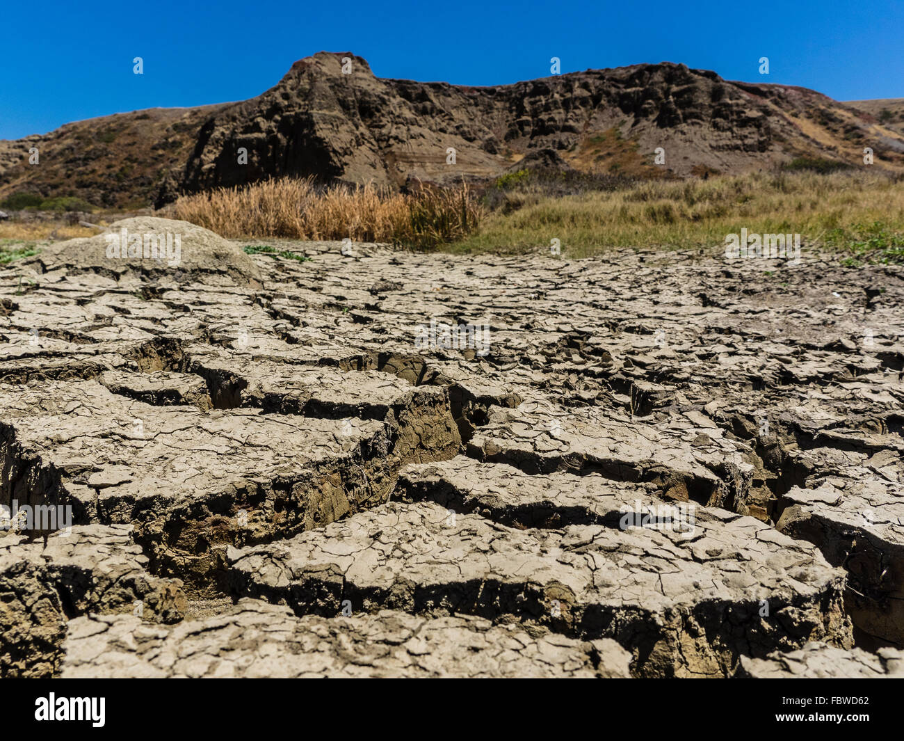 A close-up view of dried out mud flats with large cracks and peeling ...
