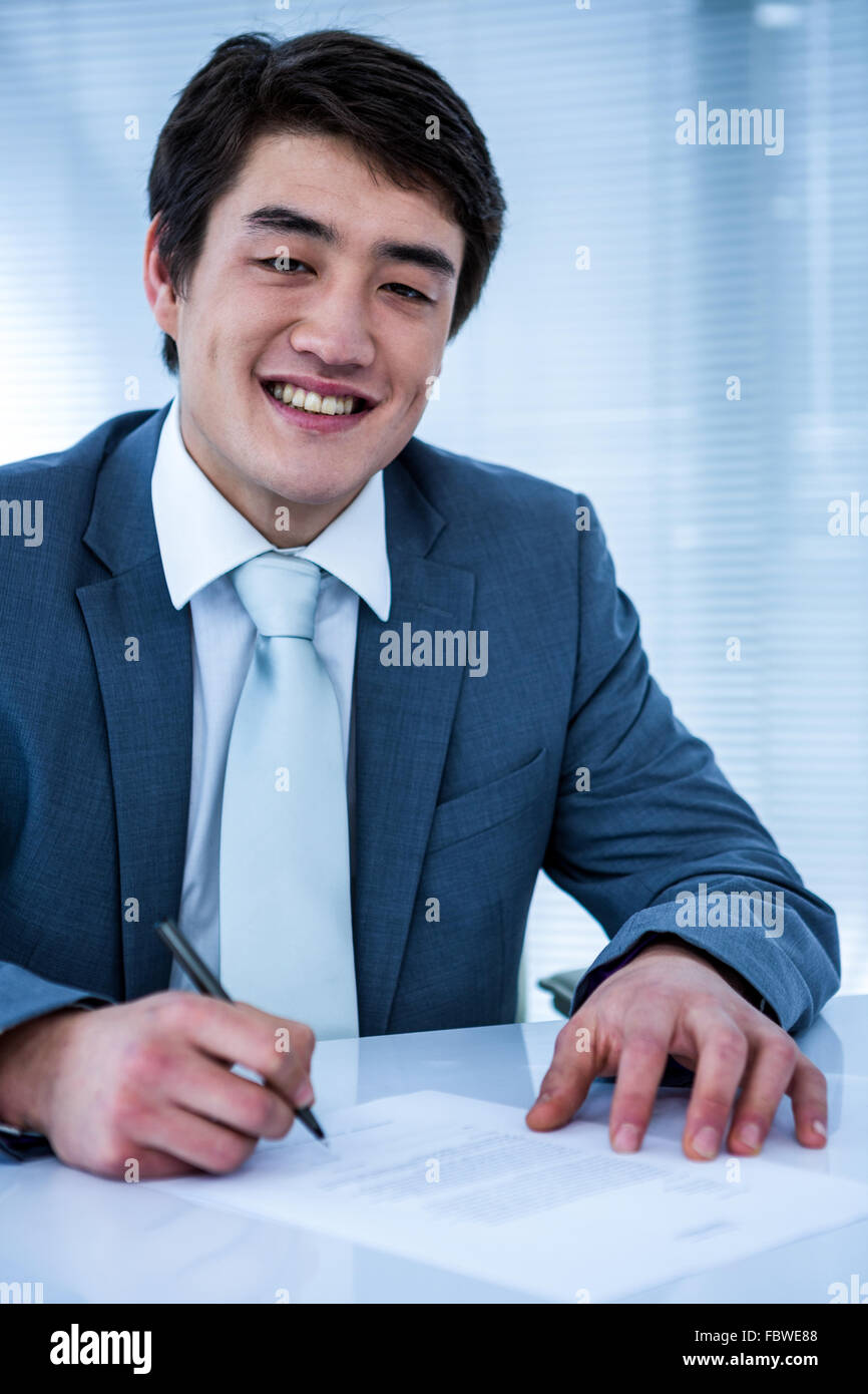 Smiling asian businessman signing a contract Stock Photo - Alamy