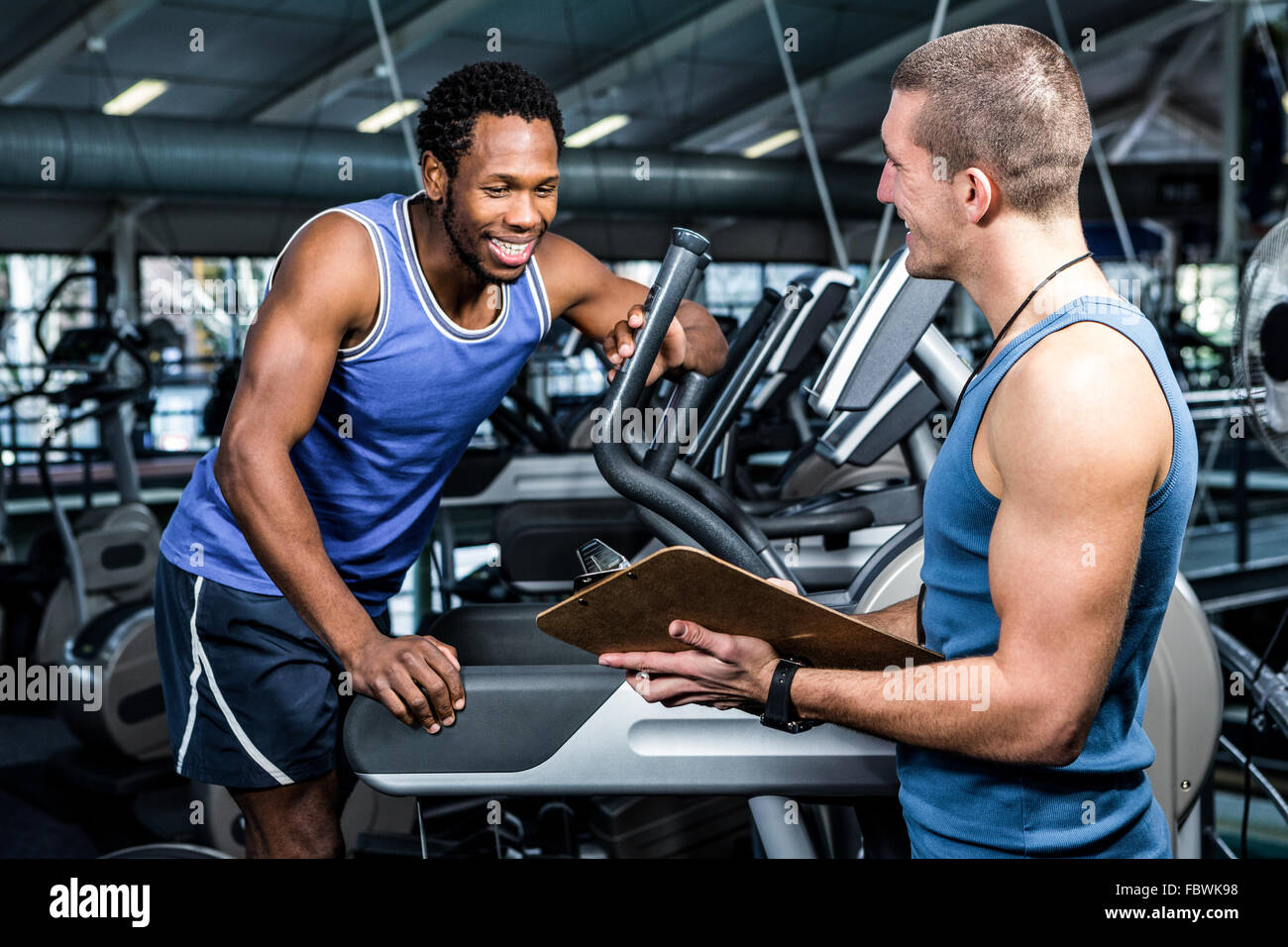Muscular man discussing performance with trainer Stock Photo - Alamy