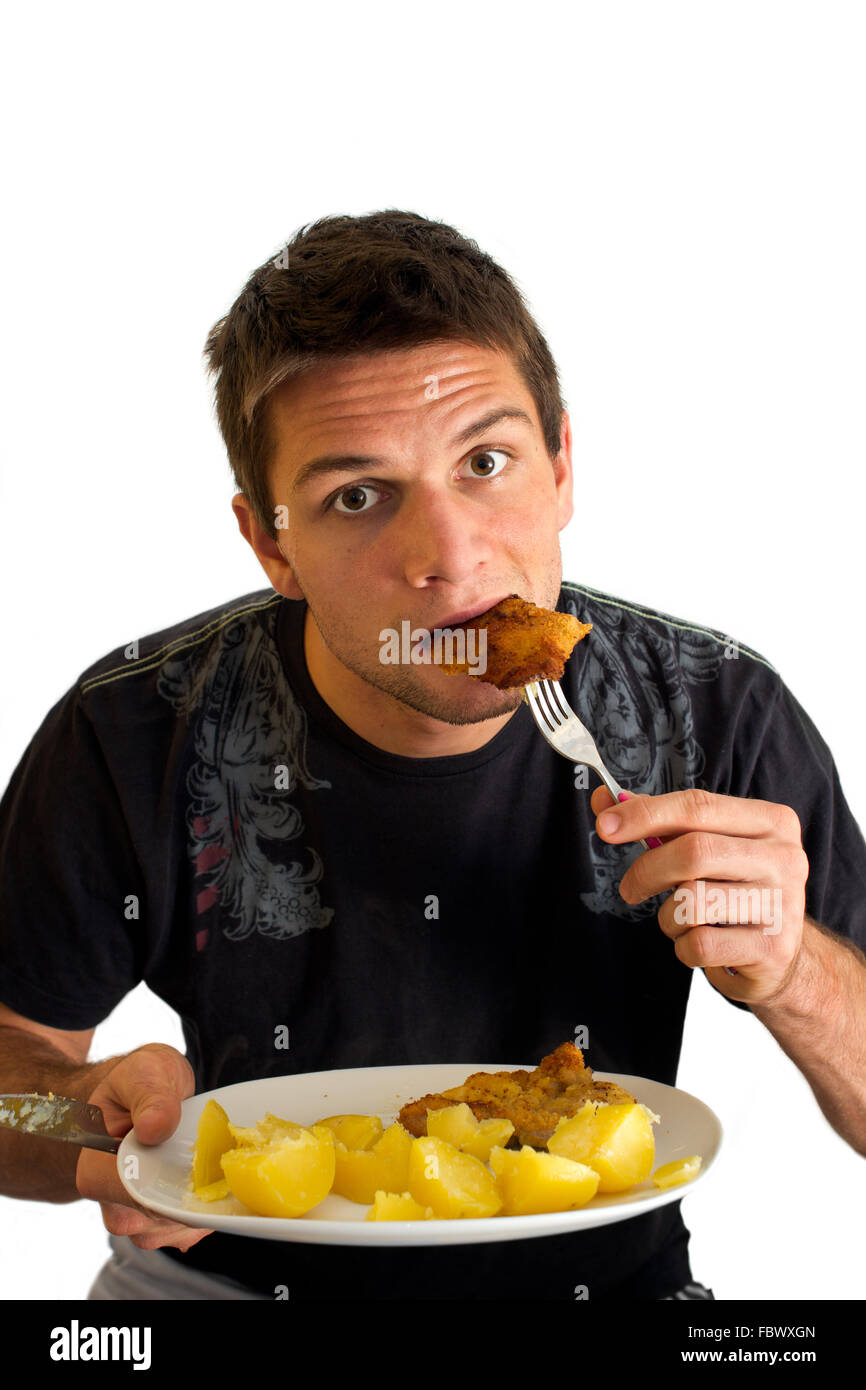 Young man eating a Schnitzel and potatoes Stock Photo - Alamy