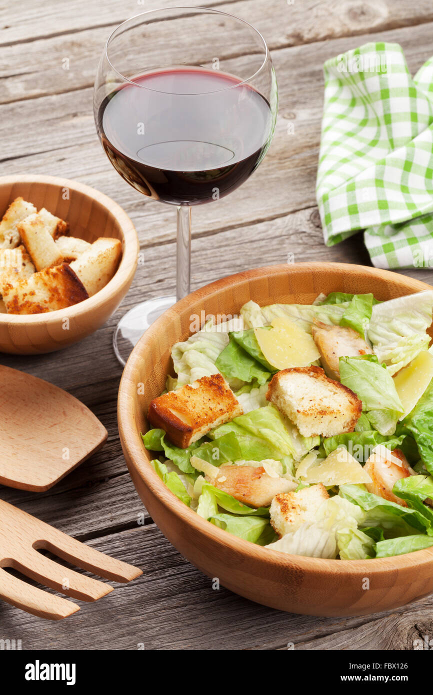 Fresh healthy caesar salad and red wine glass on wooden table Stock ...