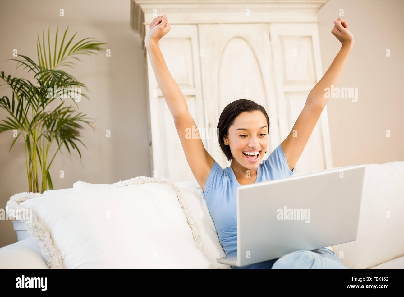 Happy woman using laptop and raising arms Stock Photo - Alamy