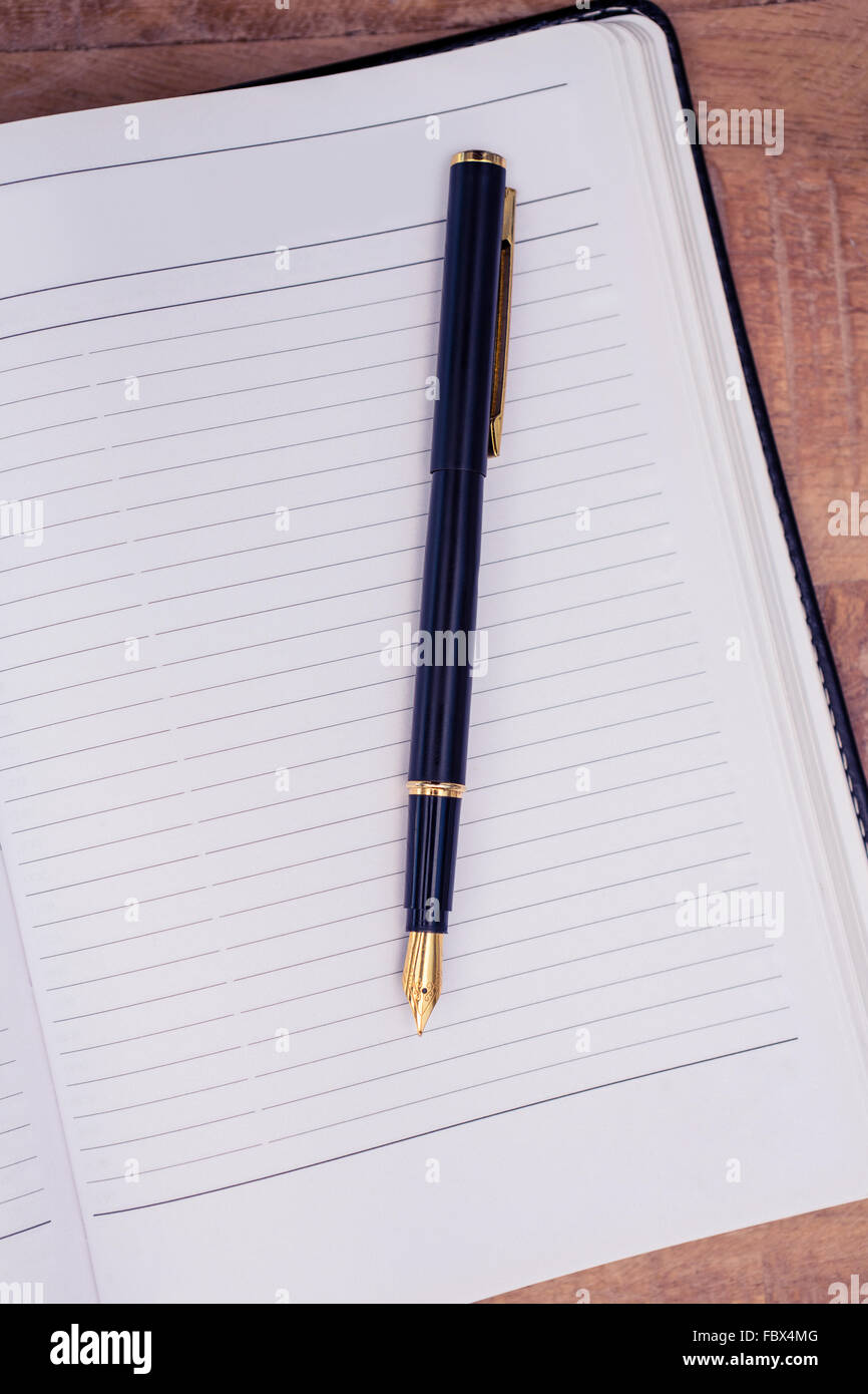 Pen on open book at table Stock Photo - Alamy