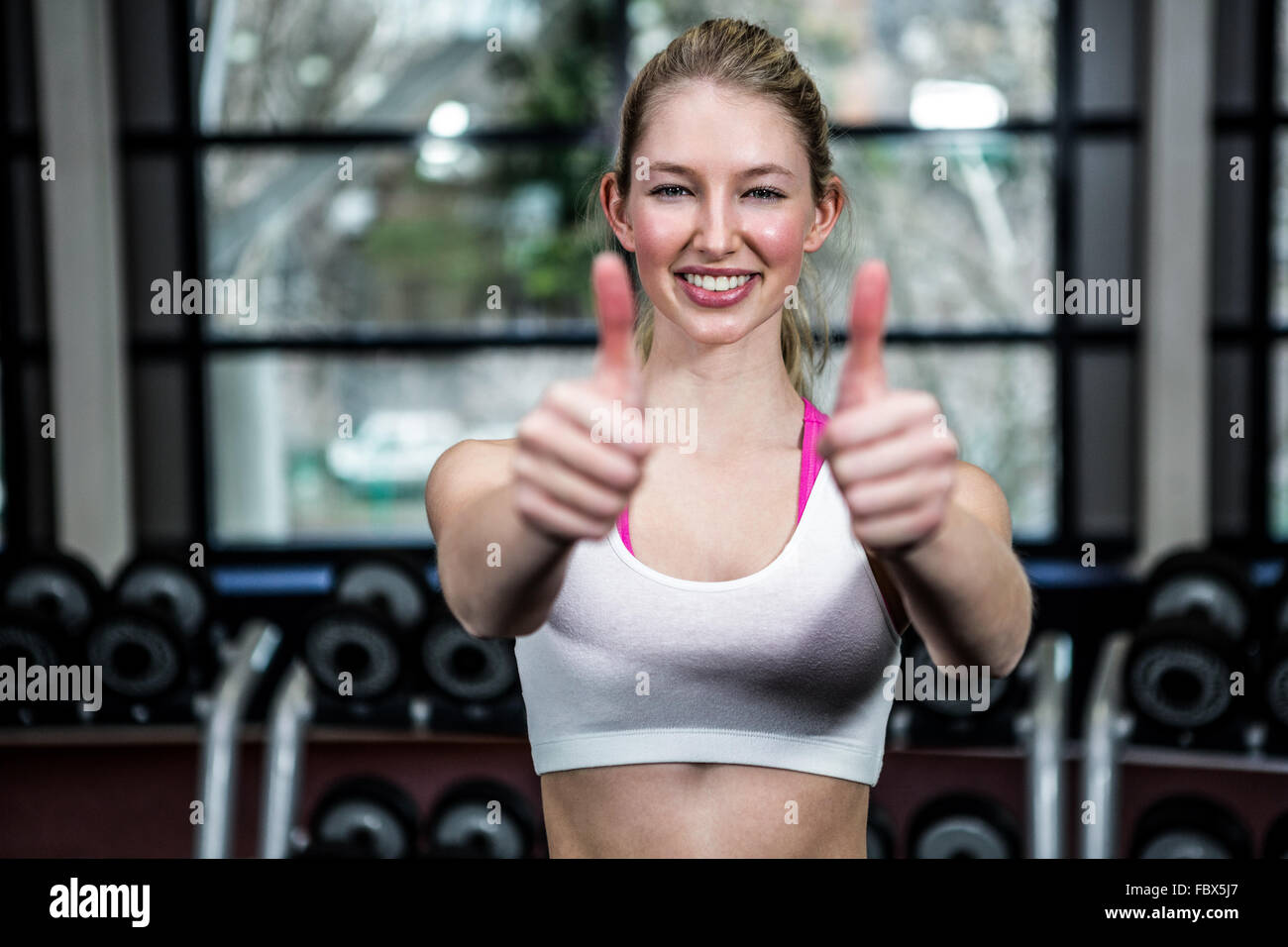 Smiling fit woman showing thumbs up Stock Photo - Alamy