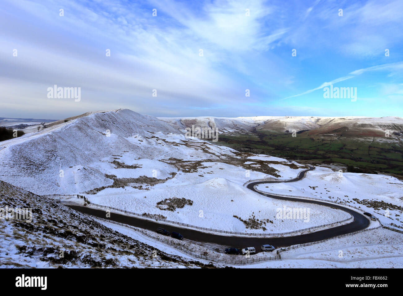 Winding road to Edale below snowy Rushup Edge and distant Kinder Scout ...
