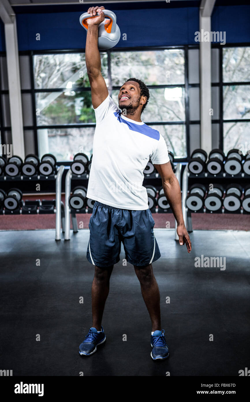 Smiling muscular man lifting kettlebells Stock Photo - Alamy