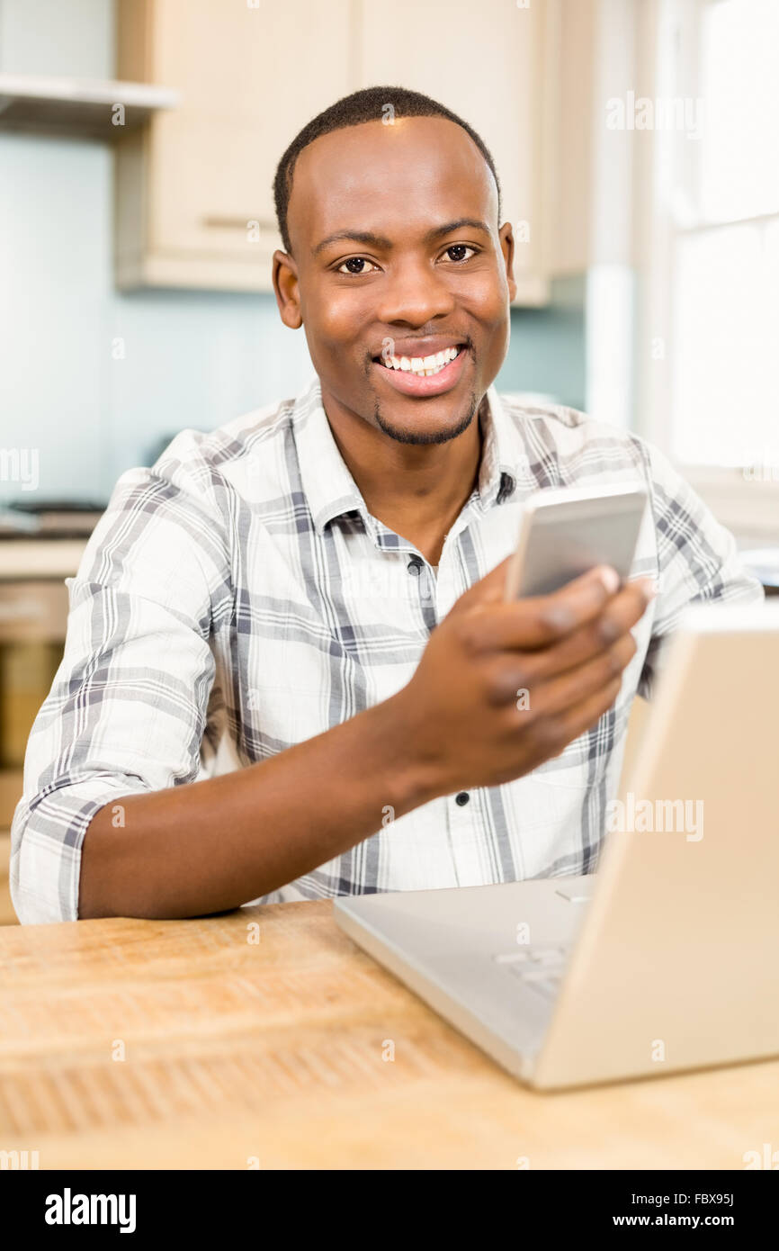 Handsome man holding smartphone in the kitchen Stock Photo - Alamy