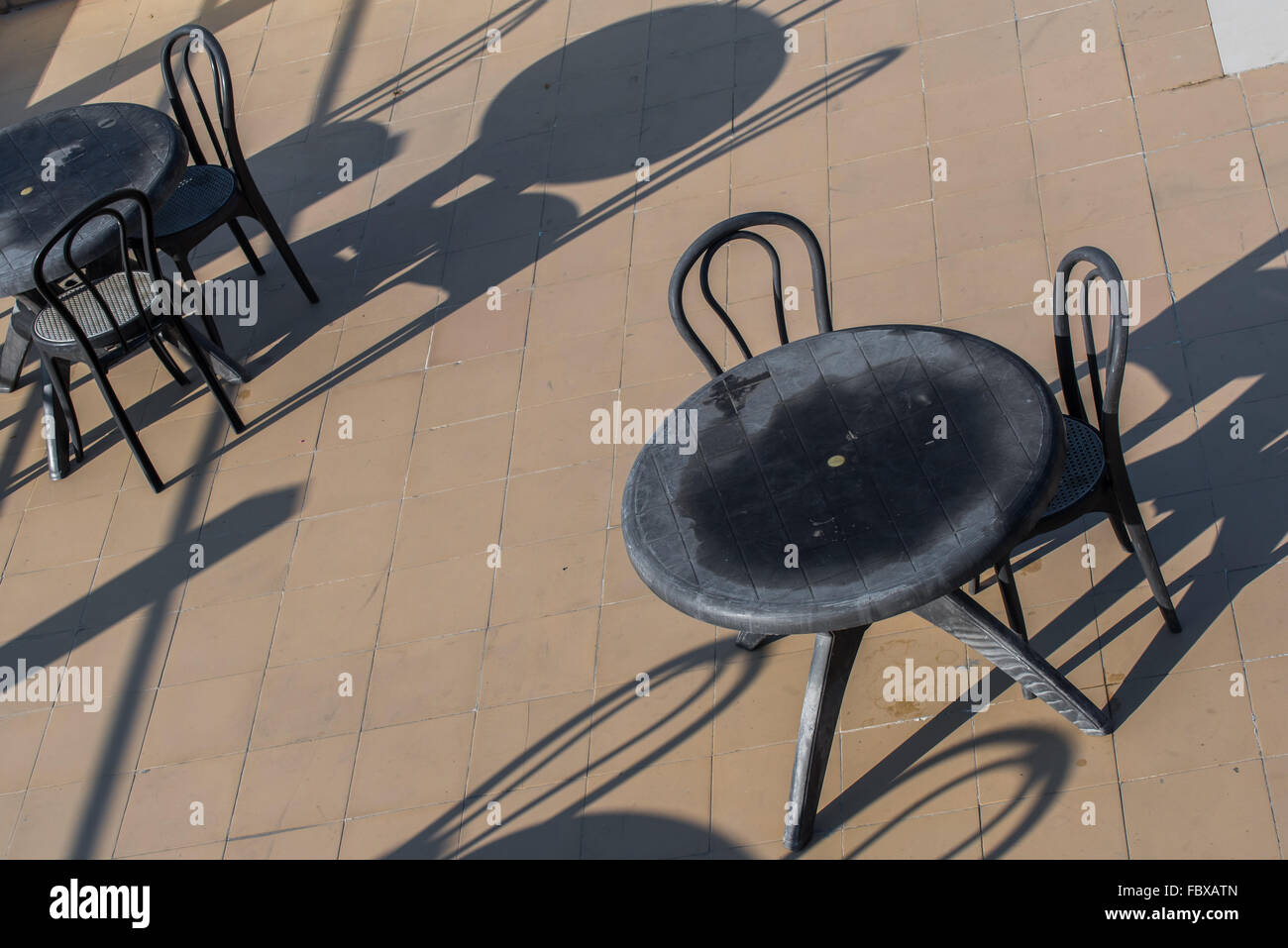 Alfresco dining. Outdoor black metal table and chairs casting deep ...