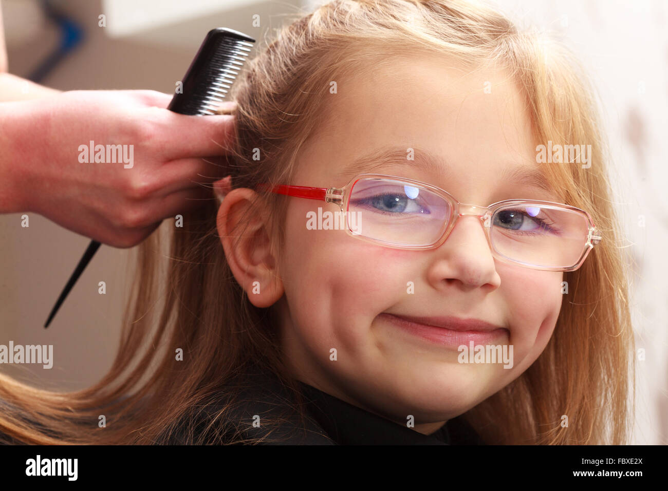 Hairdresser combing hair little girl child in hairdressing beauty salon Stock Photo - Alamy