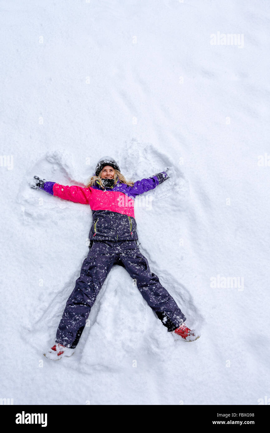 Girl laying on snow and making angel Stock Photo - Alamy