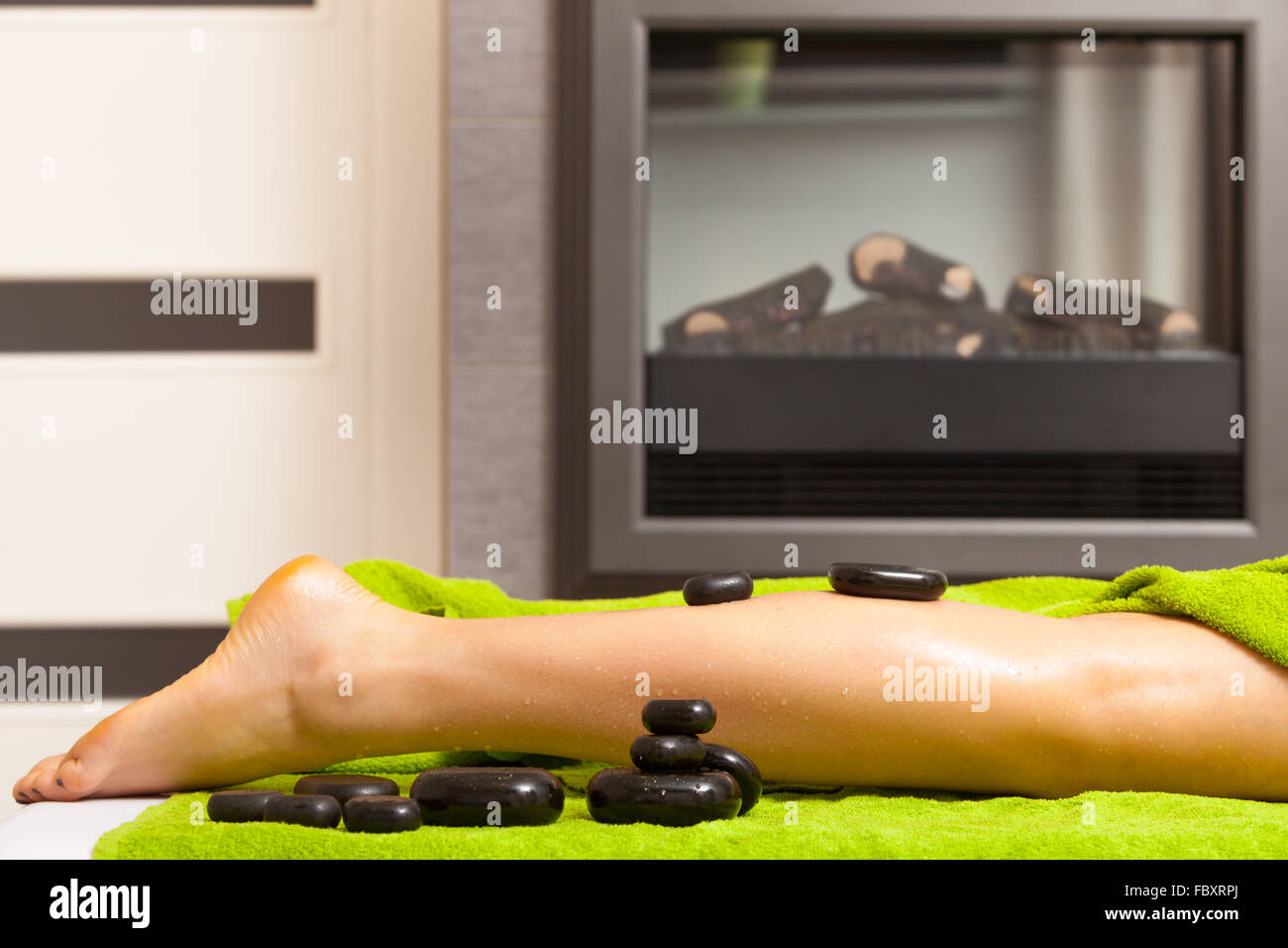Beauty salon. Woman getting spa hot stone legs massage Stock Photo - Alamy
