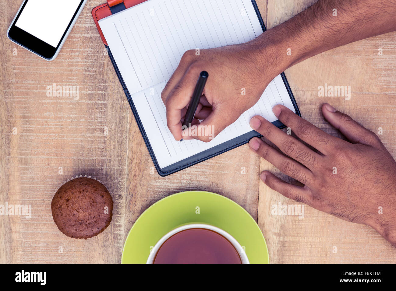Cropped image of man writing on diary at table Stock Photo - Alamy