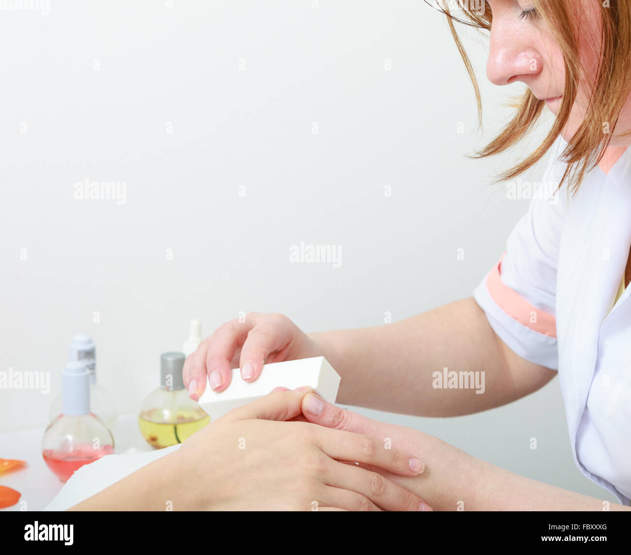 Beautician With File Filing Nails Female Client In Beauty Salon Stock