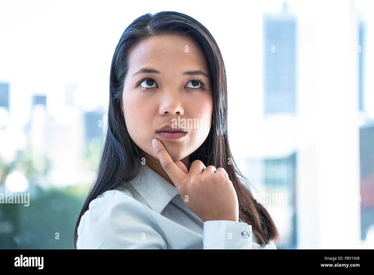 Thoughtful businesswoman with finger on chin Stock Photo - Alamy