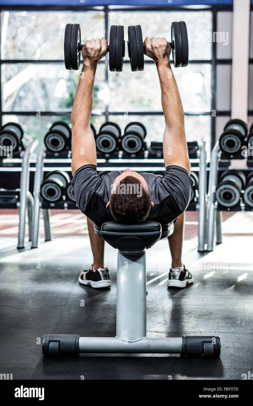 Muscular man lifting dumbbells while lying on bench Stock Photo - Alamy