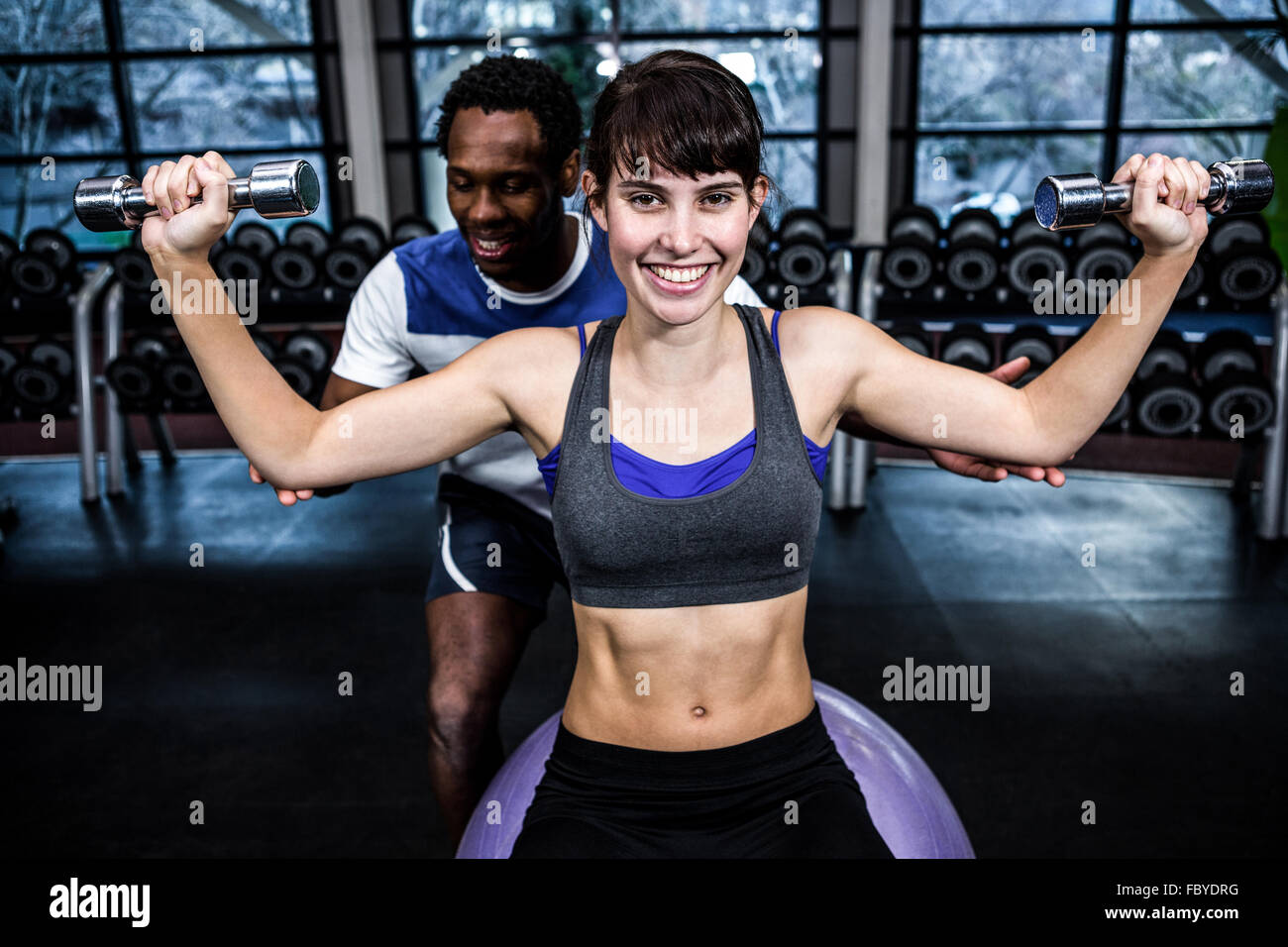 Male trainer helping woman during dumbbells exercise Stock Photo - Alamy