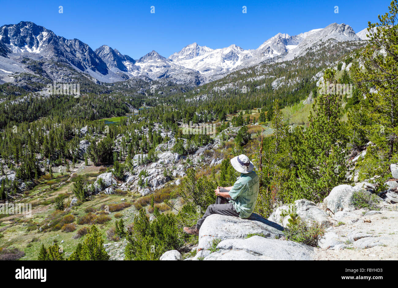 Hiker relaxes at overlook with view of Little Lakes Valley in Rock ...