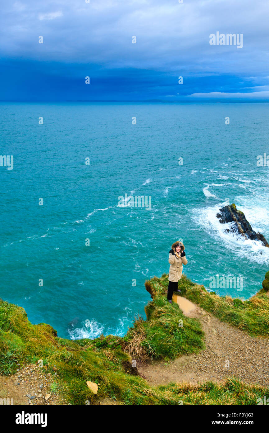 Woman standing on rock cliff by the ocean Co. Cork Ireland Stock Photo ...