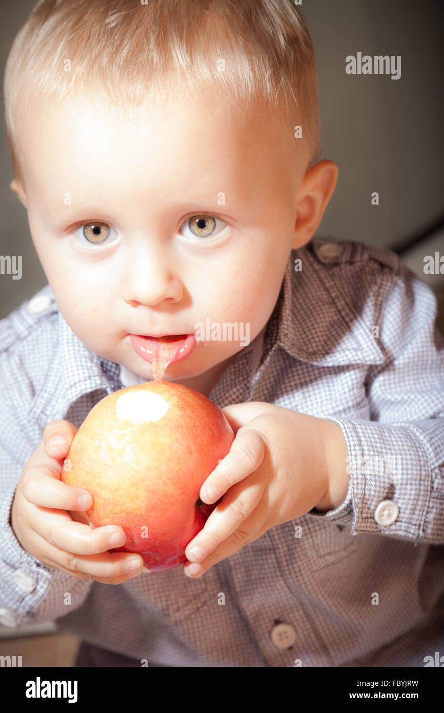 Cute baby boy eating red apple fruit Stock Photo - Alamy